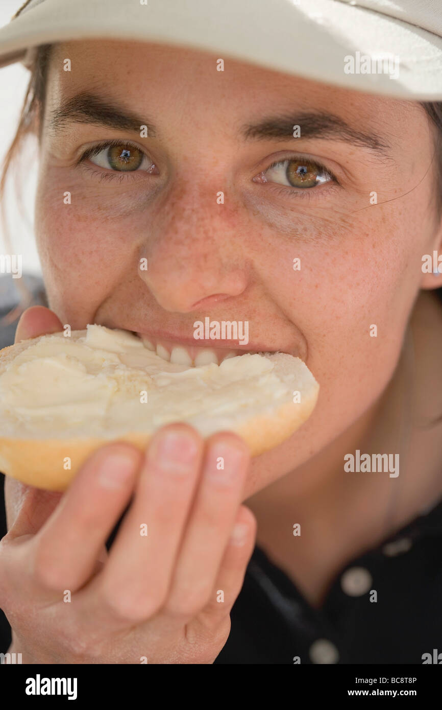Woman biting into a buttered bread roll Stock Photo - Alamy