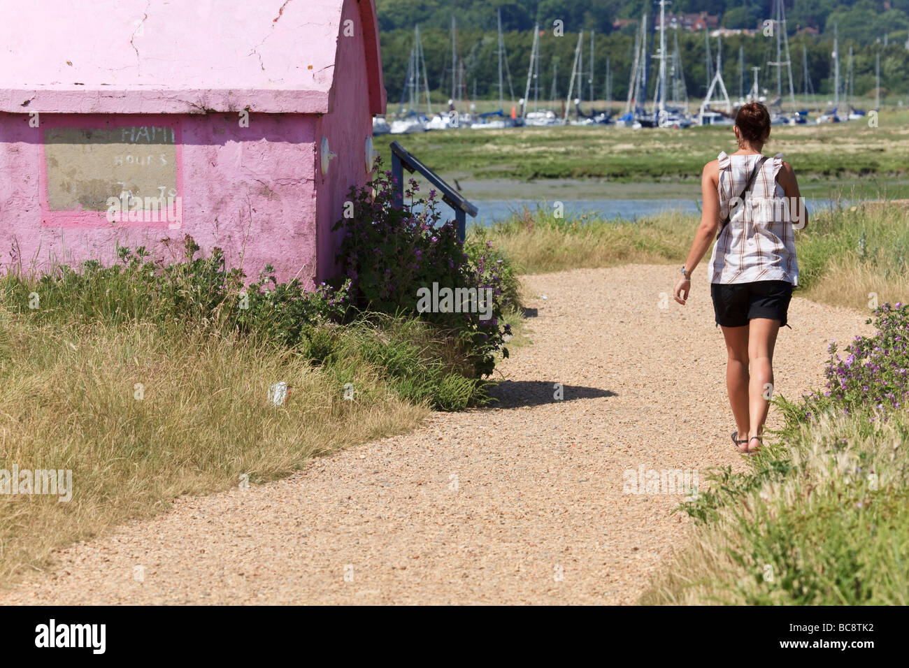 An attractive young woman walks on the Solent Way at Warsash passing ...