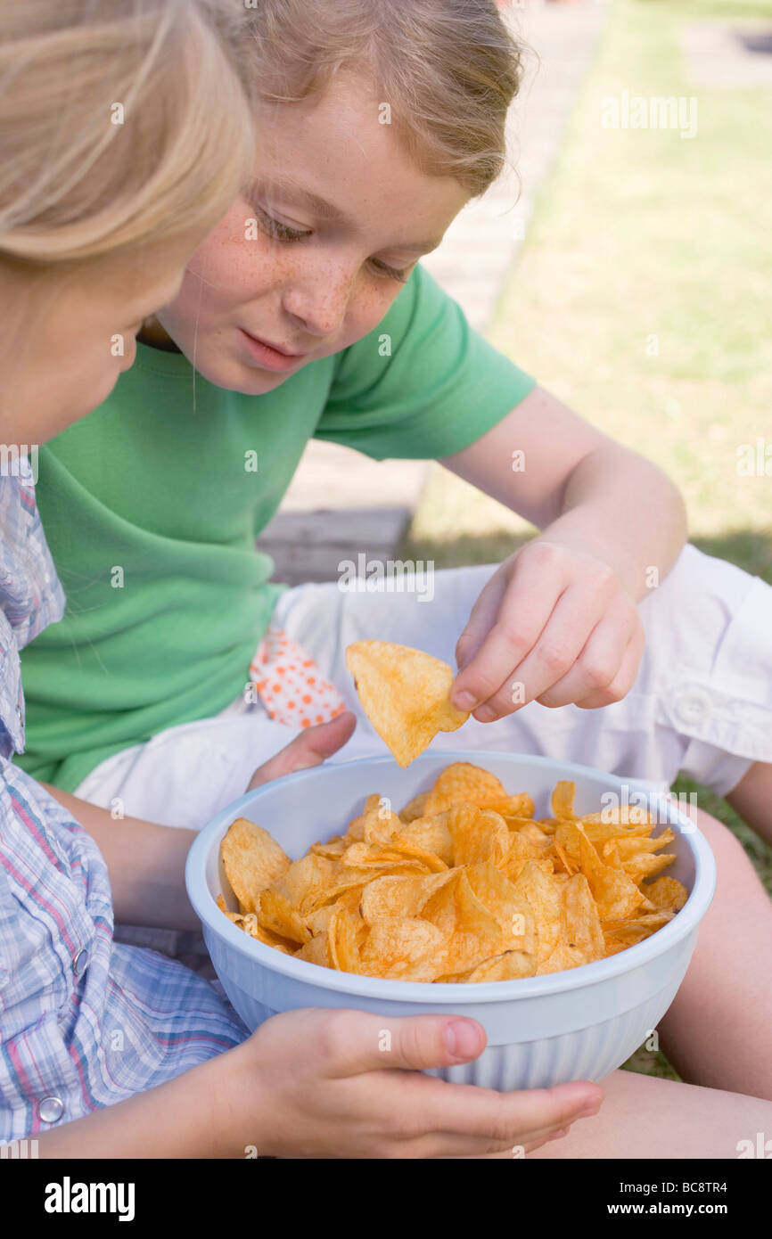 Two girls eating crisps out of doors Stock Photo - Alamy