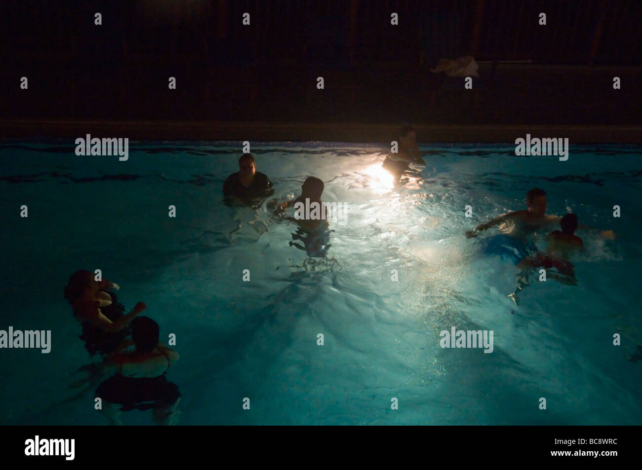 People Swimming In A Pool At Night