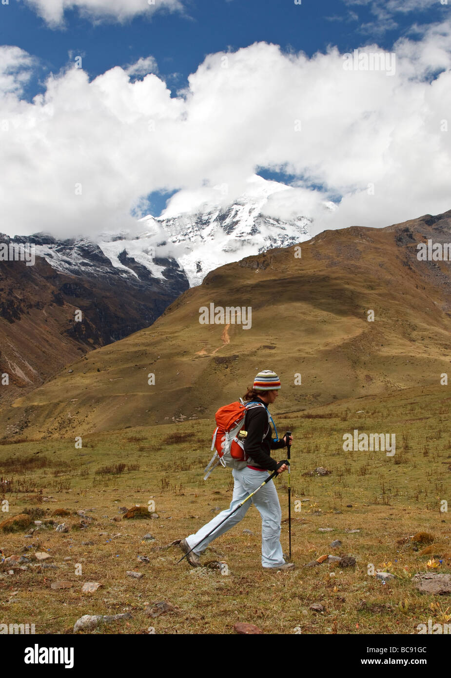 A woman treks along a hillside in Bhutan with Mt. Jomolhari in the ...