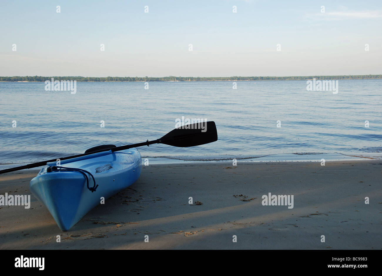Blue kayak beached beside a wide blue river under a blue sky Stock ...