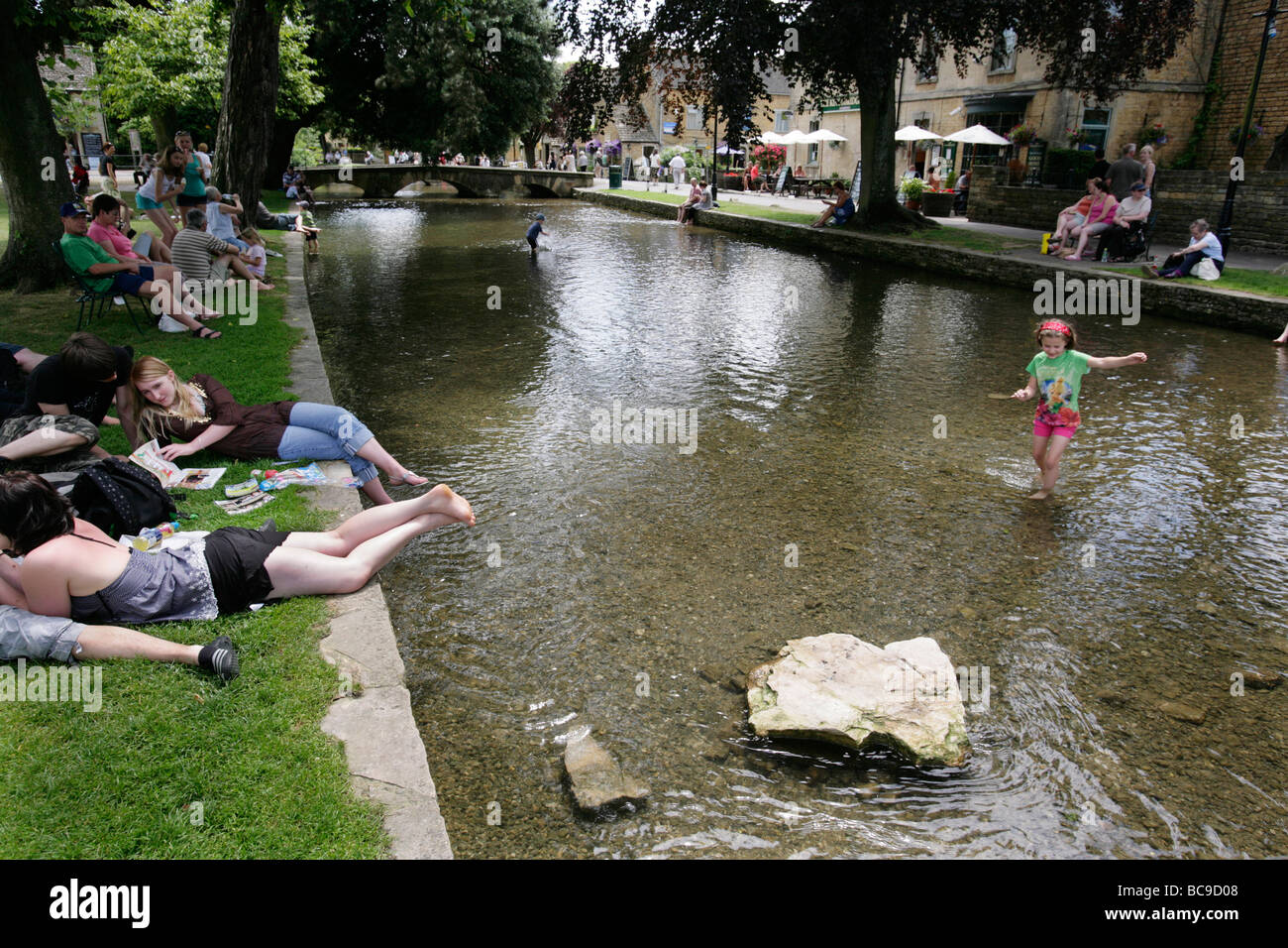 People sunbathing on the banks of the River Windrush in Bourton-on-the ...