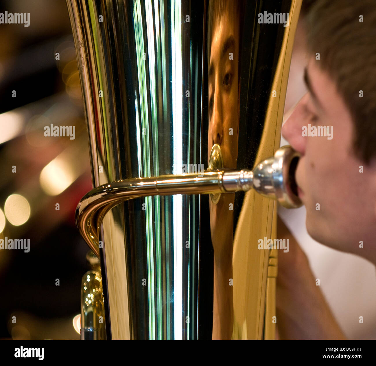 The face of a musician seen in the reflection in the shiny surface of a ...