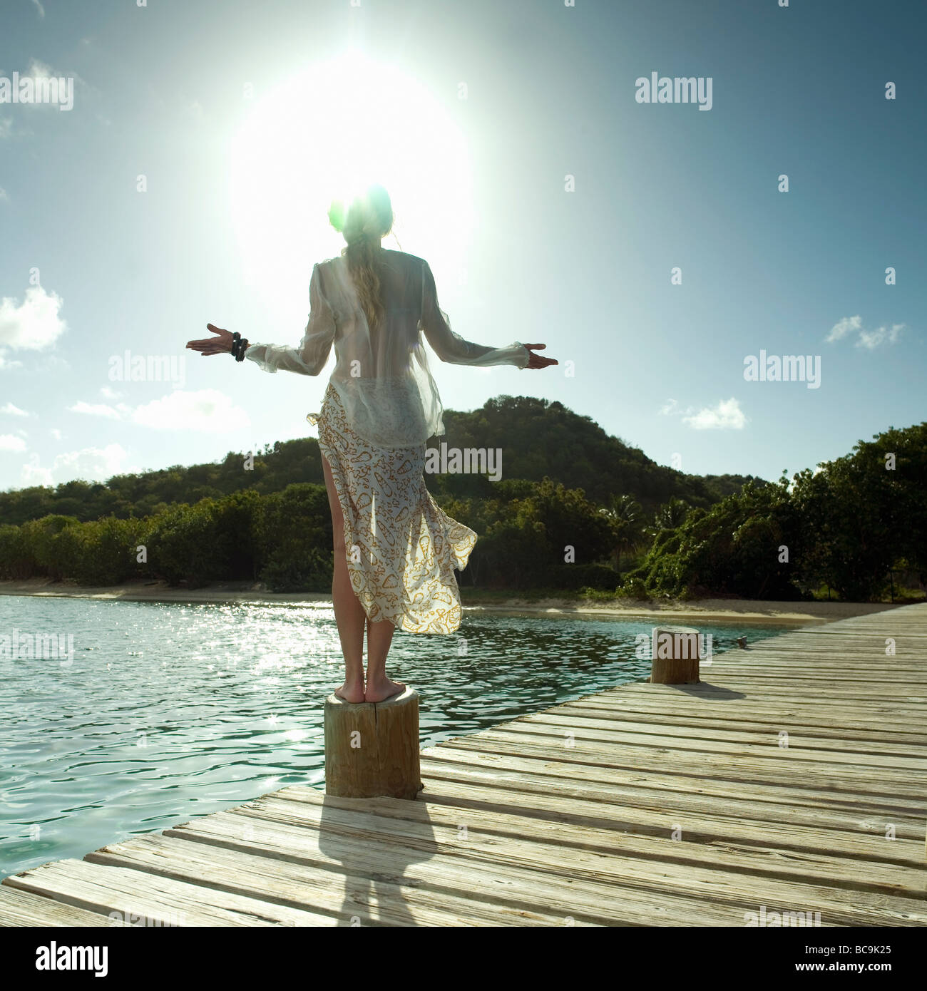 Woman standing on post with arms outstretched, rear view Stock Photo ...