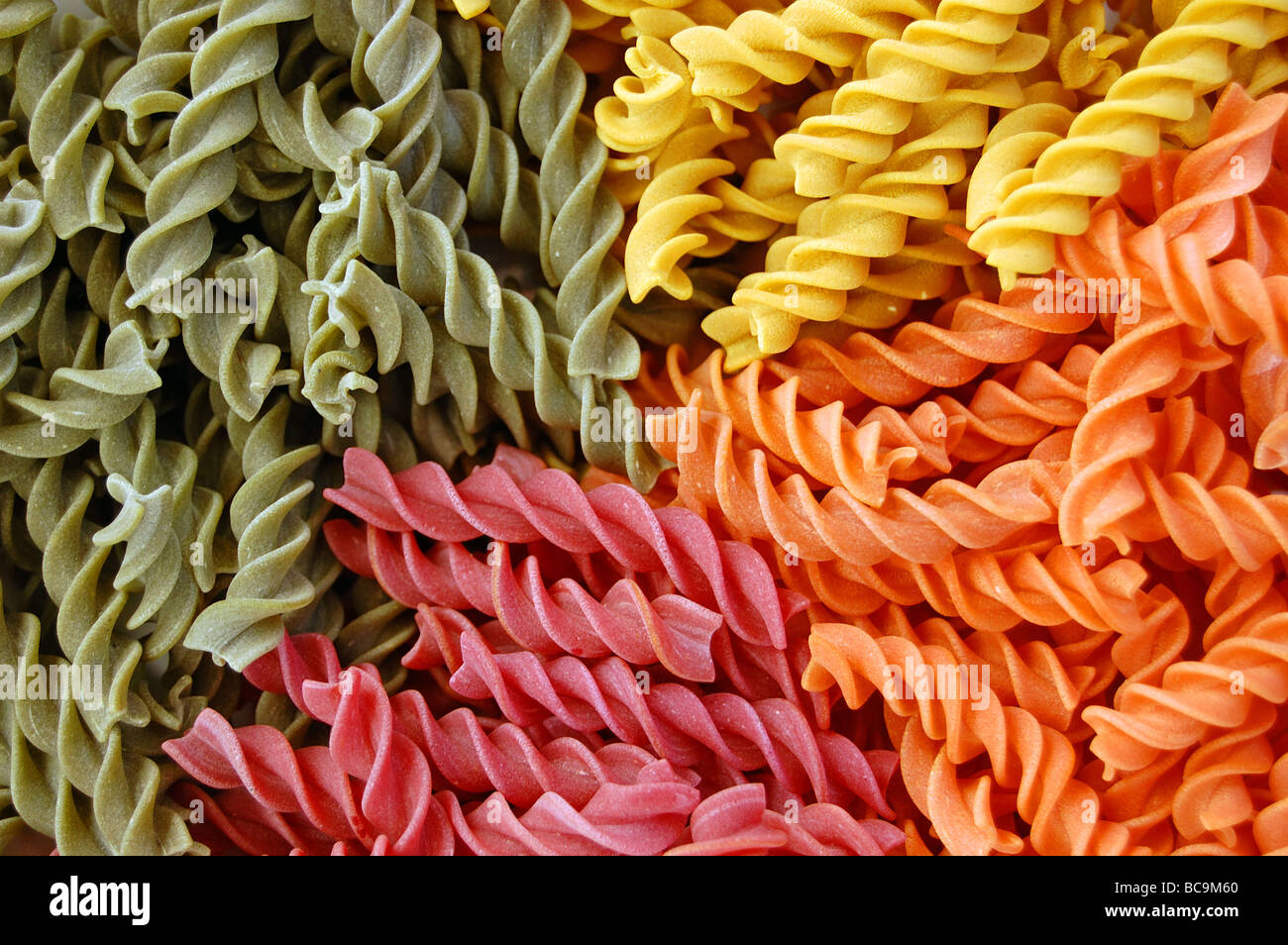 Four different flavors of fusilli pasta. Italian food background detail ...