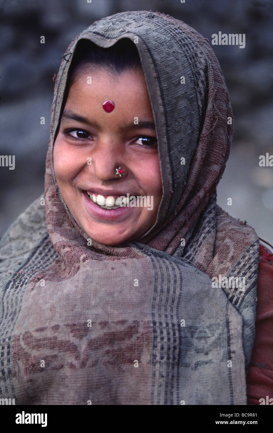 A SMILING GURUNG GIRL with a NOSE RING and a BINDI wearing a head shawl ...