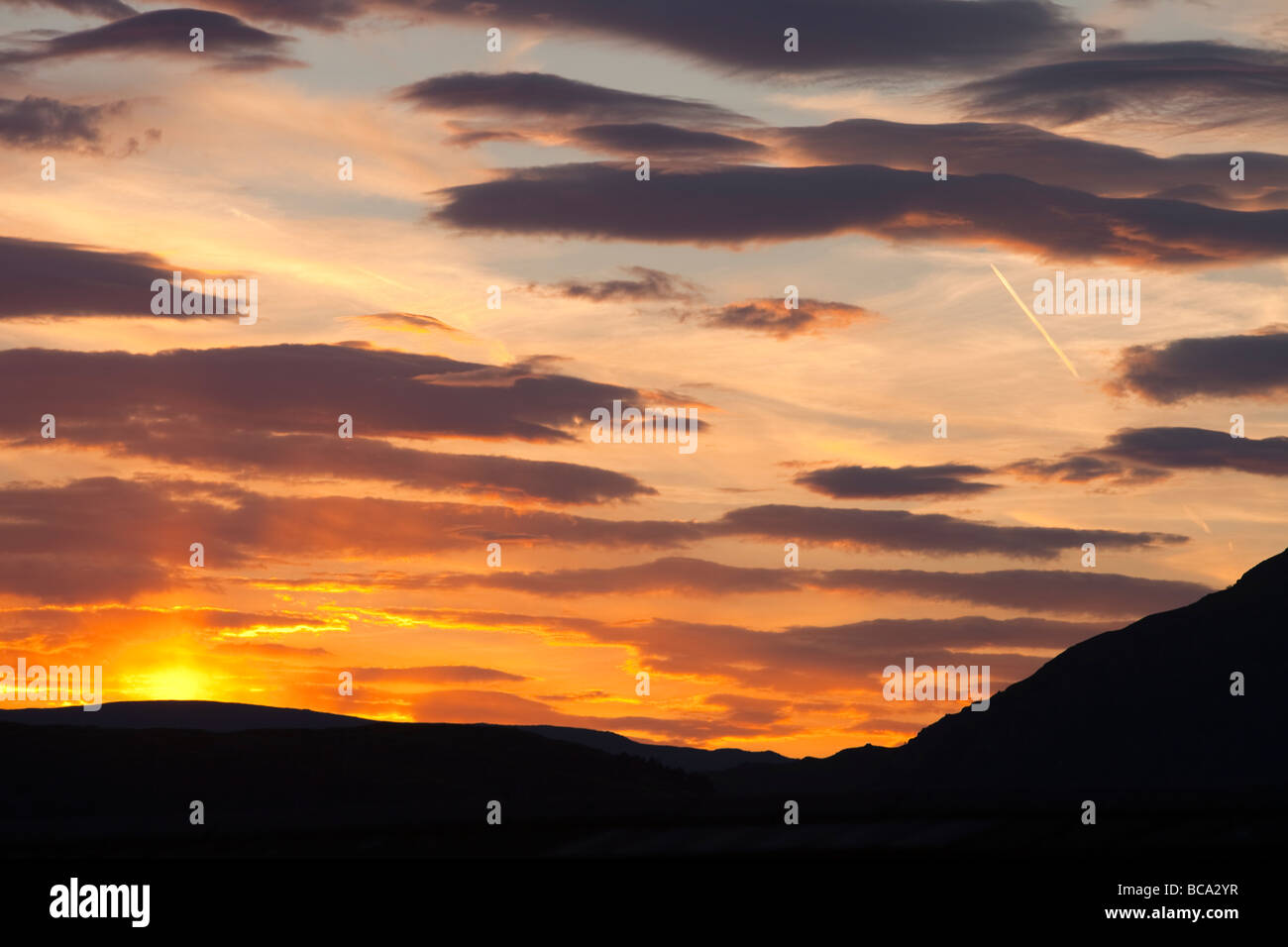 A plane flying through sunset clouds over Ambleside Cumbria UK Stock ...