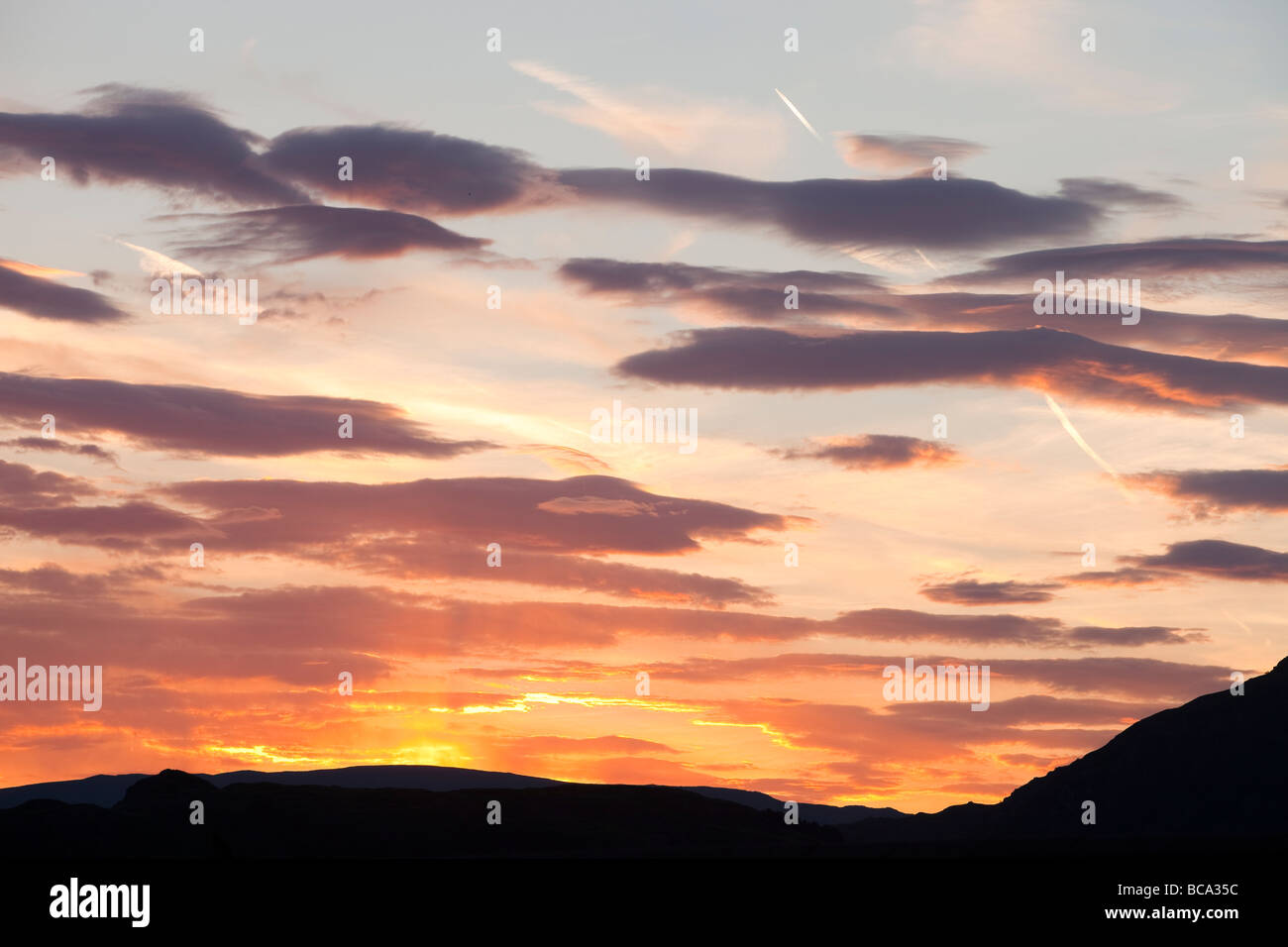 A plane flying through sunset clouds over Ambleside Cumbria UK Stock ...