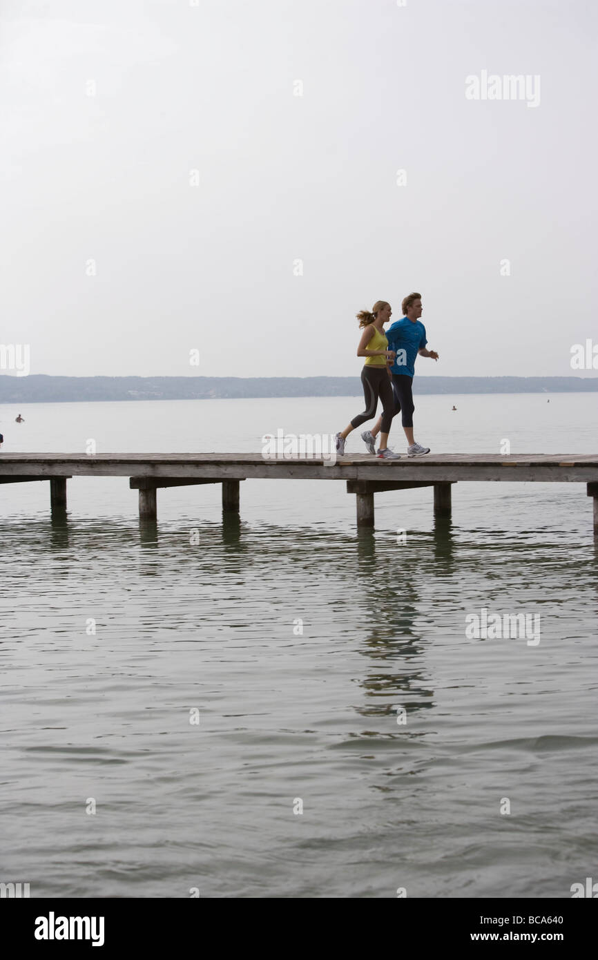 Man and woman running on jetty Stock Photo - Alamy