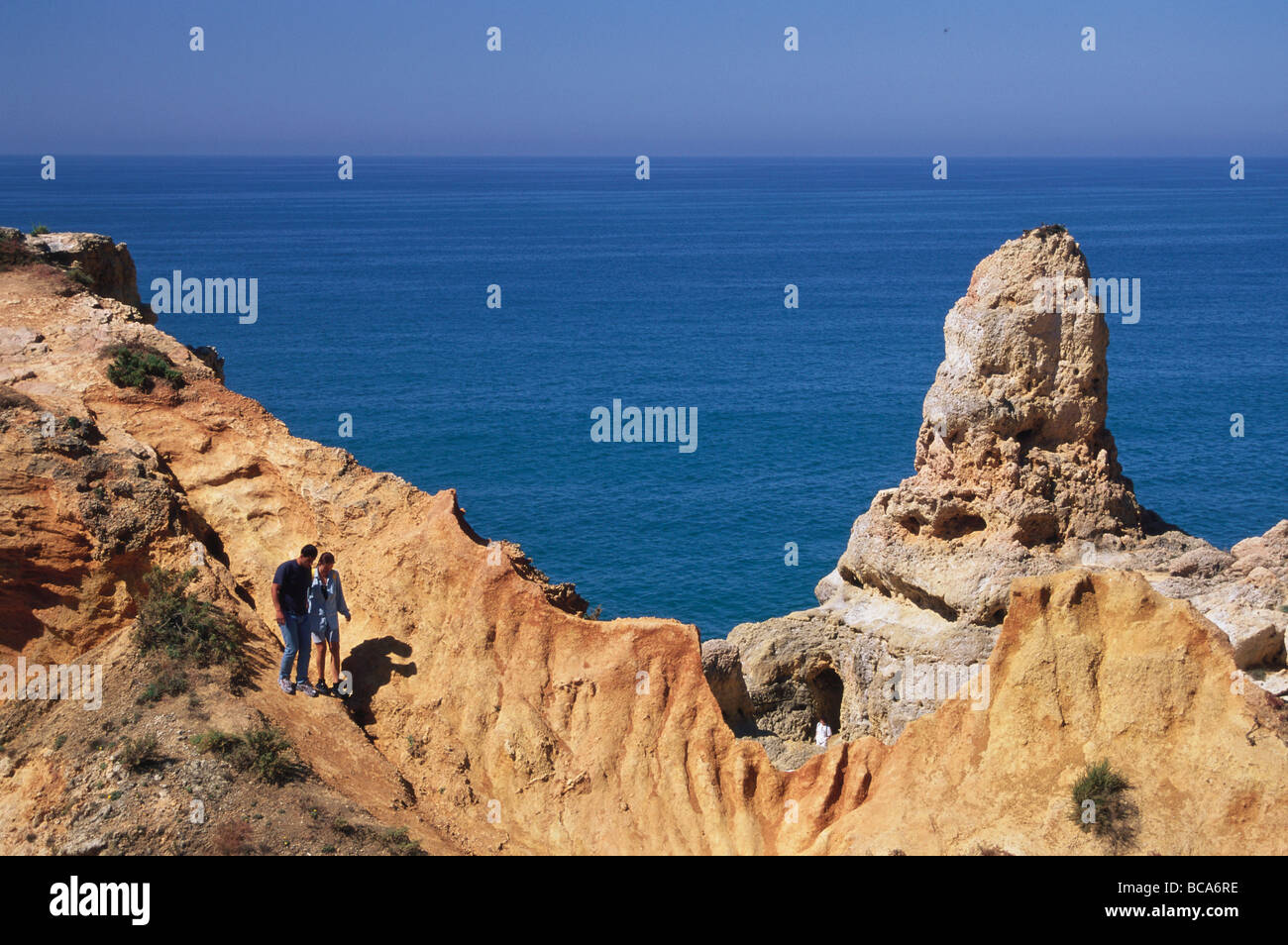 A couple walking along limestone rock, Algar Seco, Carvoeiro, Algarve ...