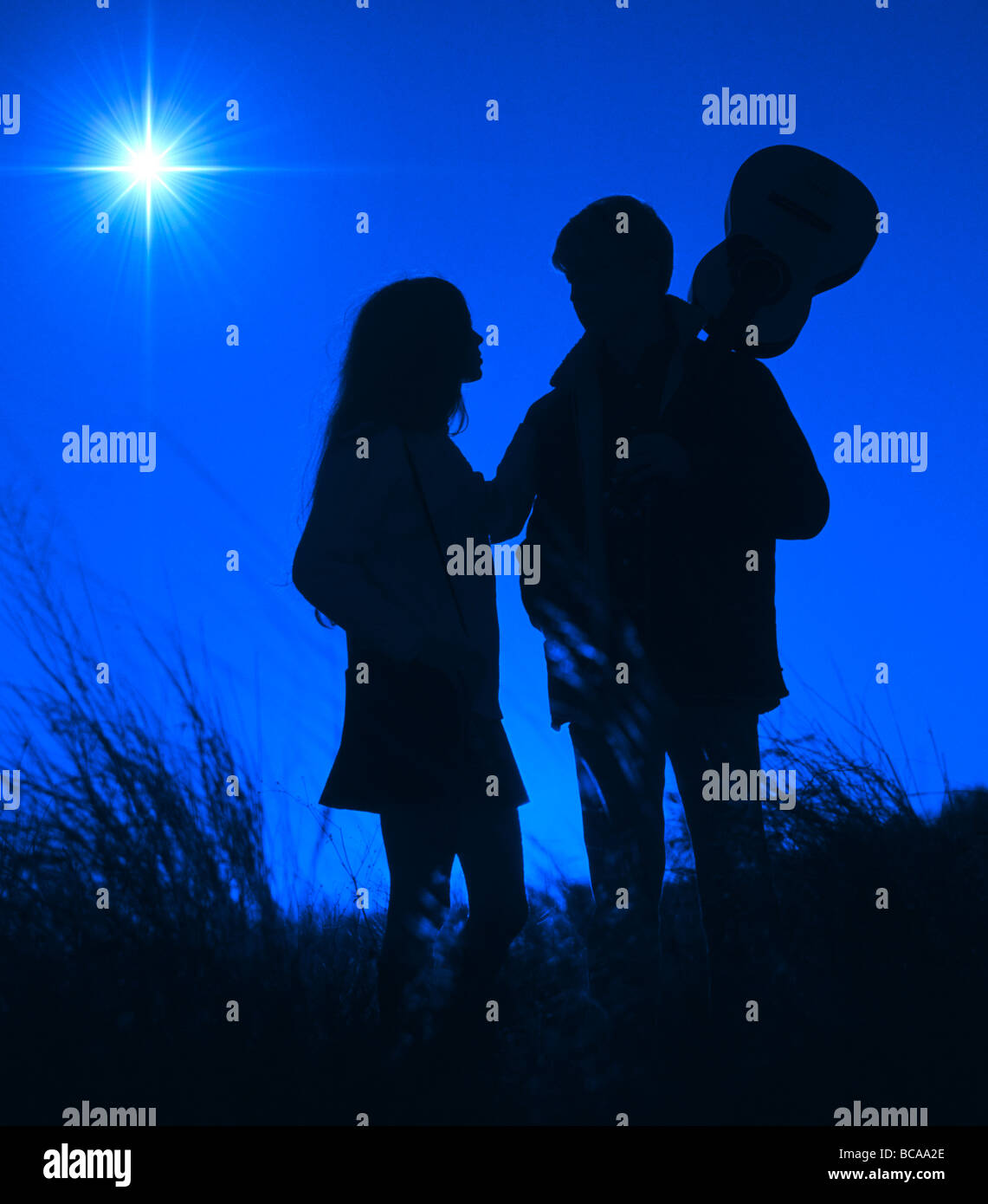 young hippie couple silhouetted against night sky and evening star ...