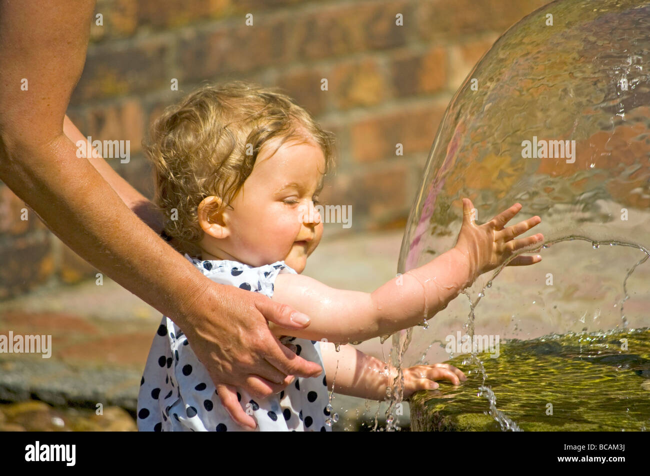 Girl playing in water fountain hi-res stock photography and images - Alamy