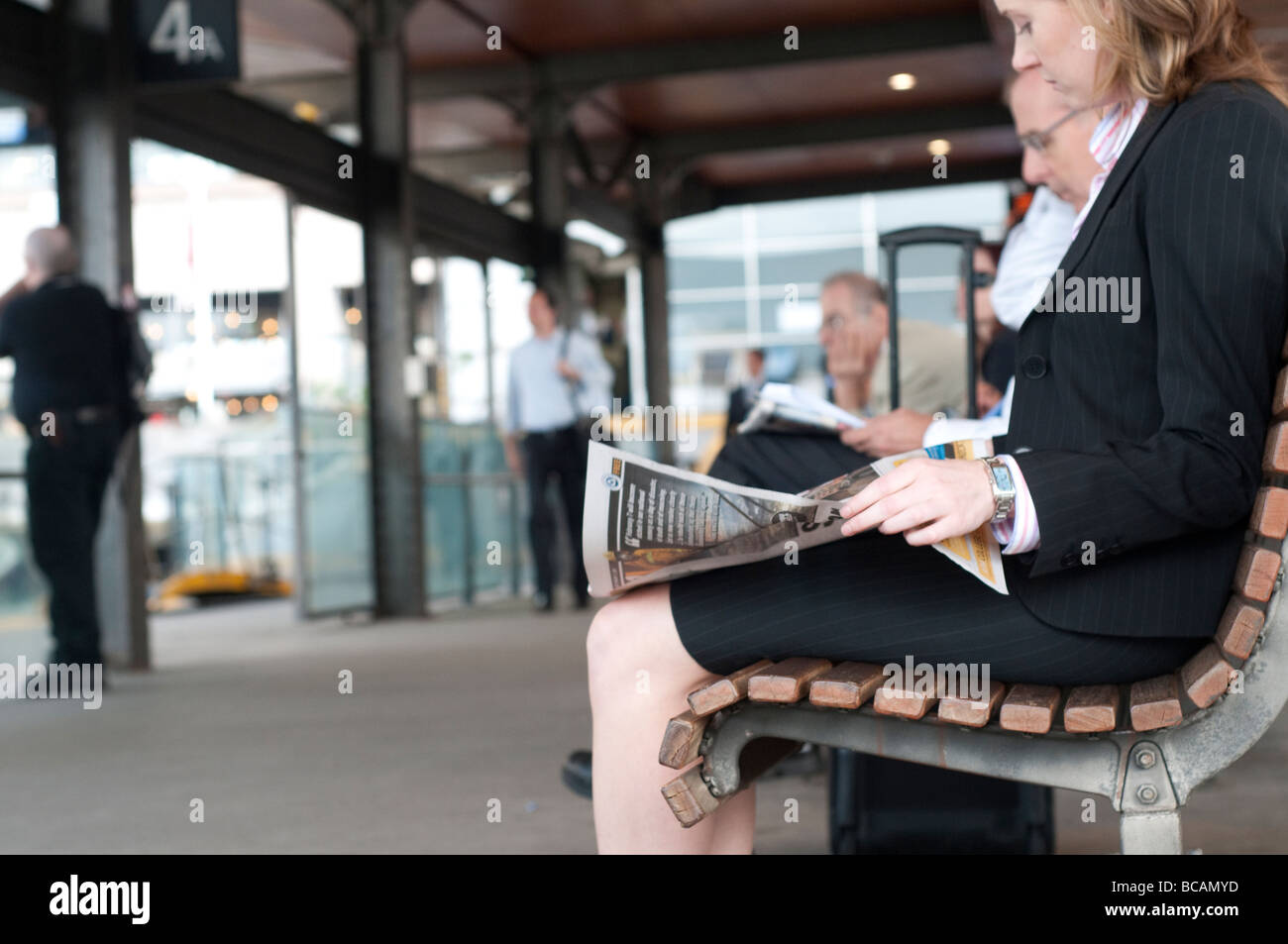 Woman commuter reading the paper in the ferry waiting area Sydney NSW ...