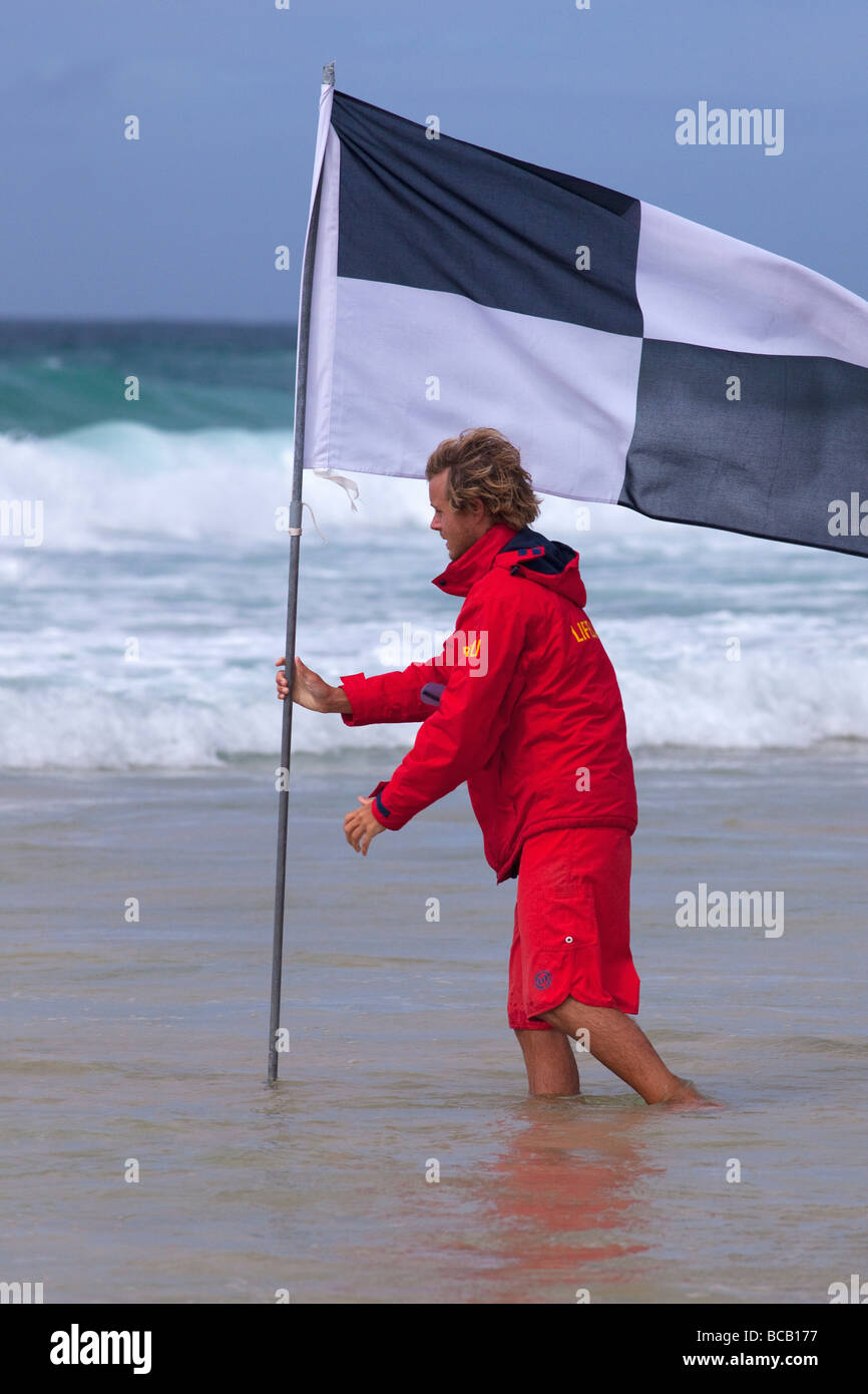 RNLI Lifeguard plants flag in waves off Porthmeor beach in summer sun ...