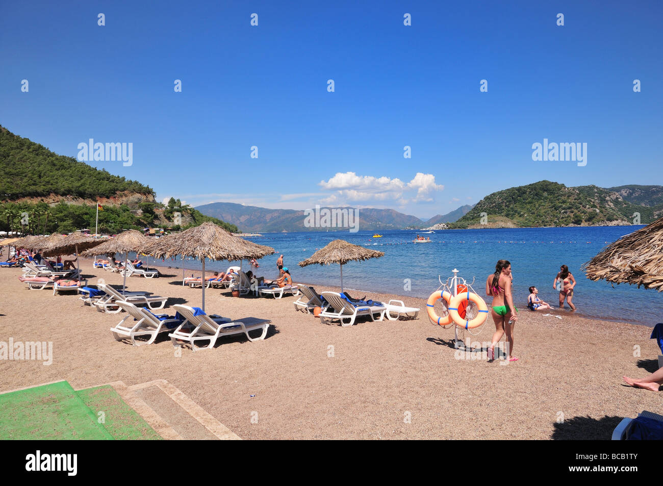 People relaxing and sunbathing on a beach with sunbeds and umbrellas ...