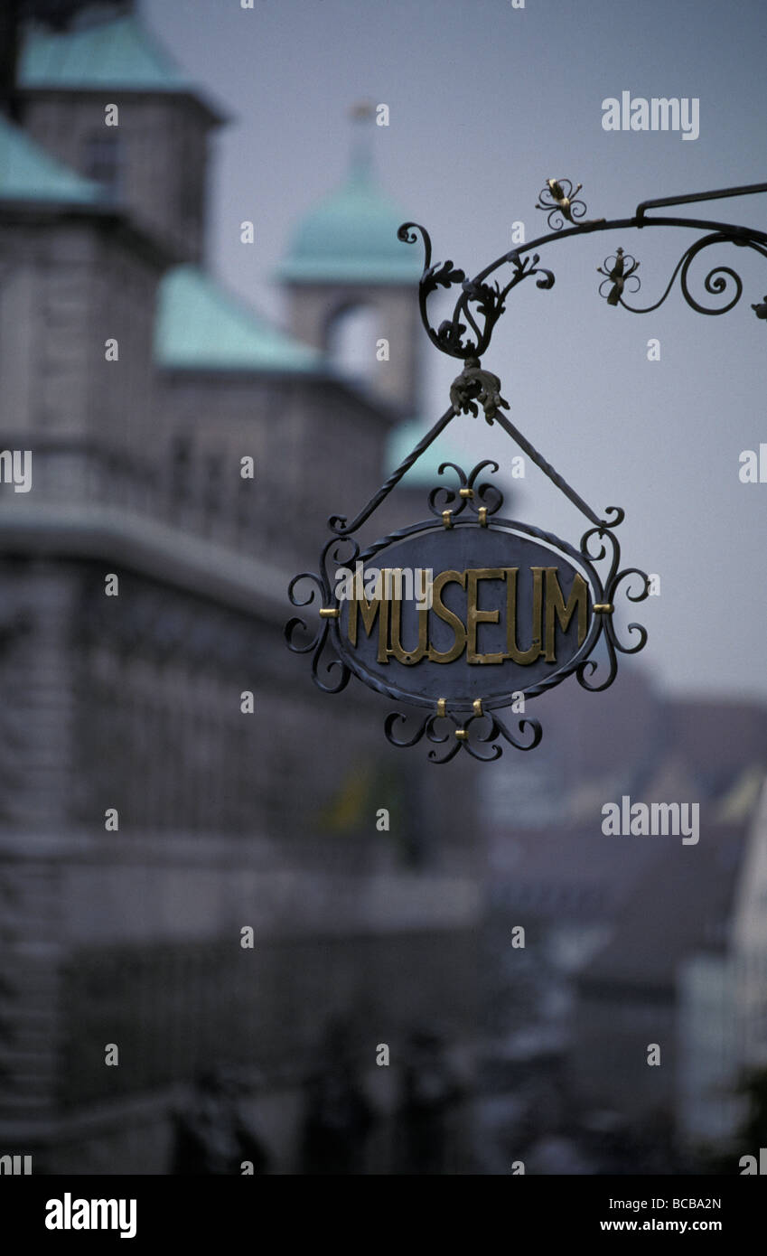 An antique-looking cast iron Museum sign hangs over a cobbled street ...