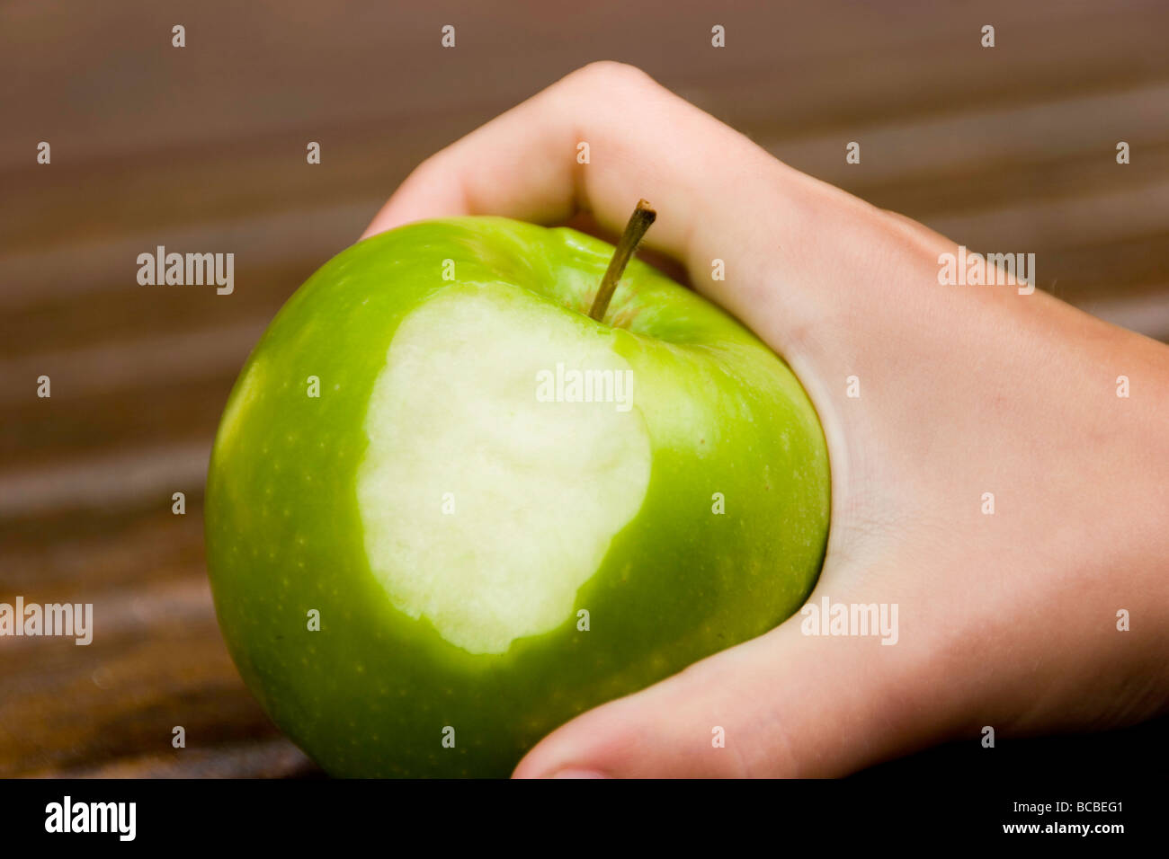 hand holding an apple with a bite taken out Stock Photo - Alamy