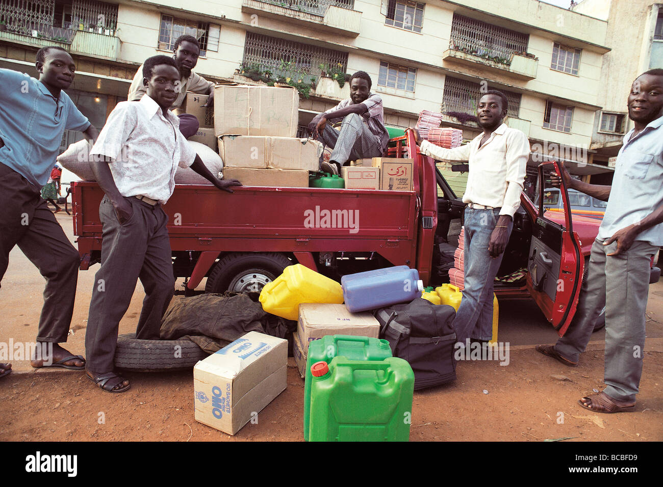 Black African men loading pickup with plastic cans cardboard cartons ...