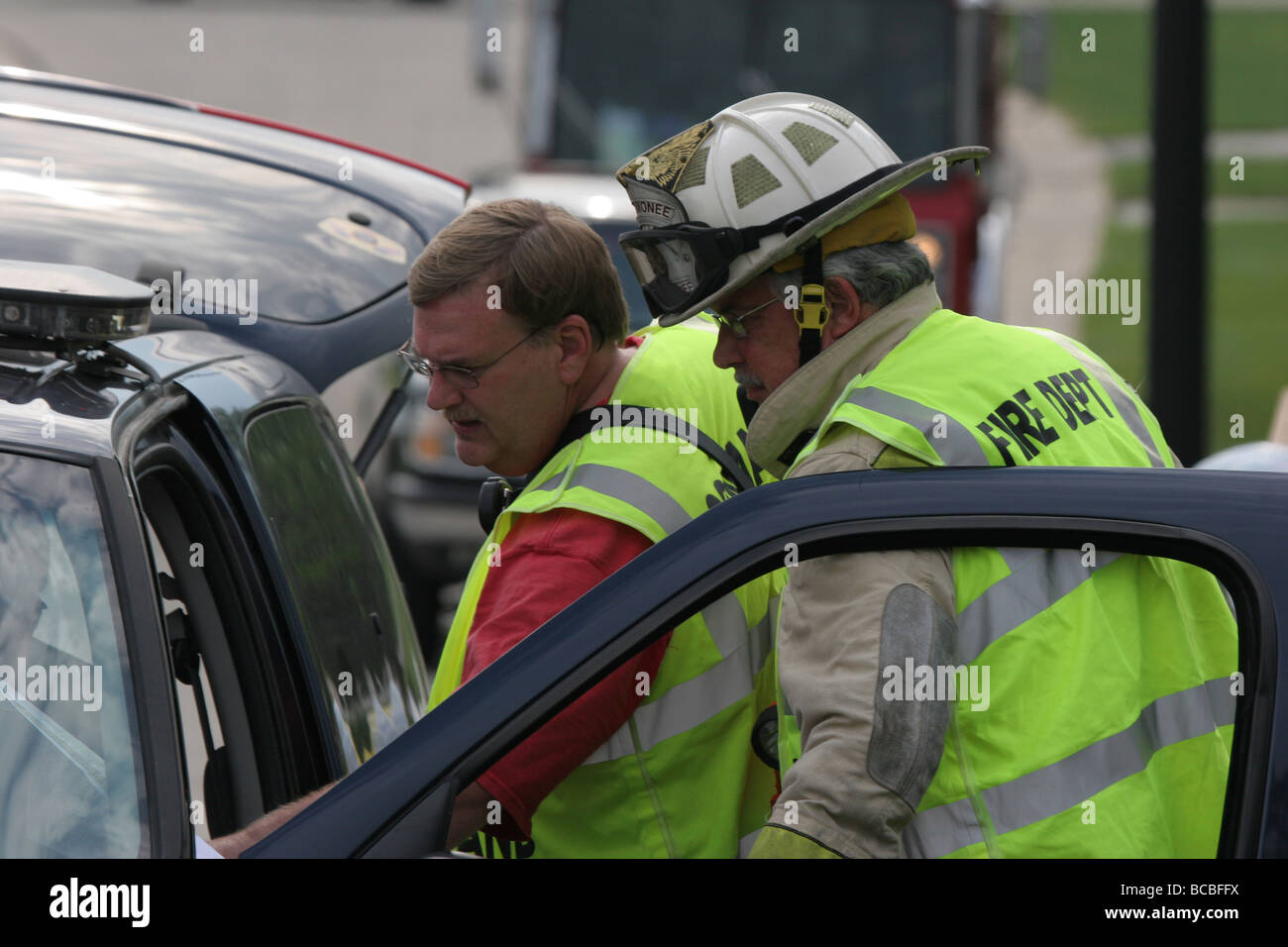 Two firefighters talking around the command post car at the scene of a ...