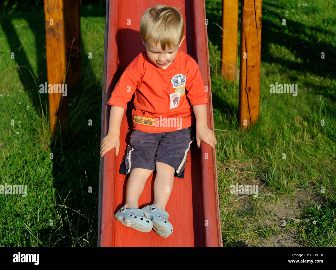 Child blond boy sliding down the slide on the playground Stock Photo ...