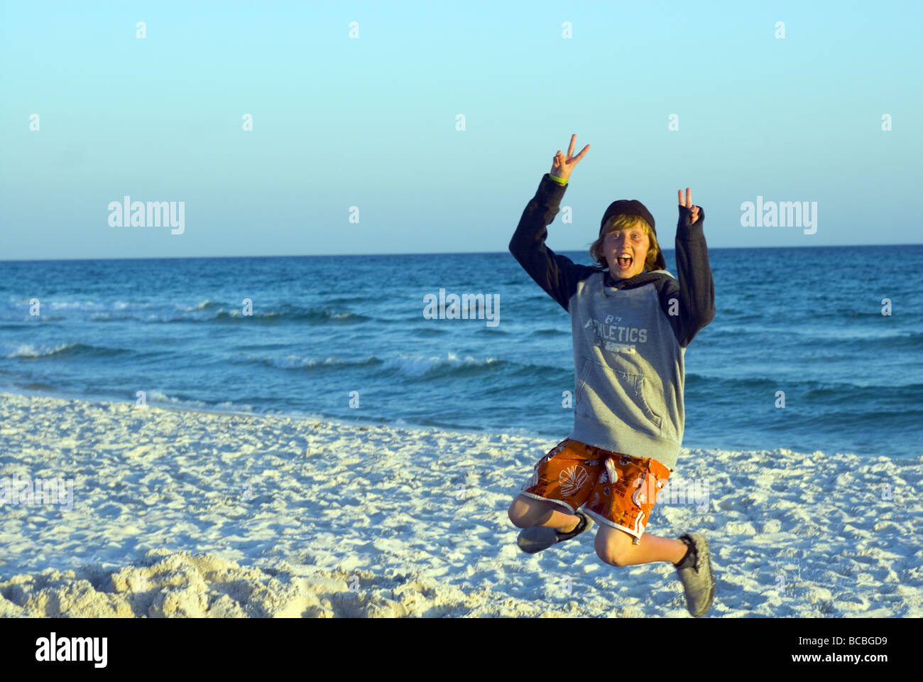 Youth Male Jumping at the Beach Showing the Peace Sign Stock Photo - Alamy