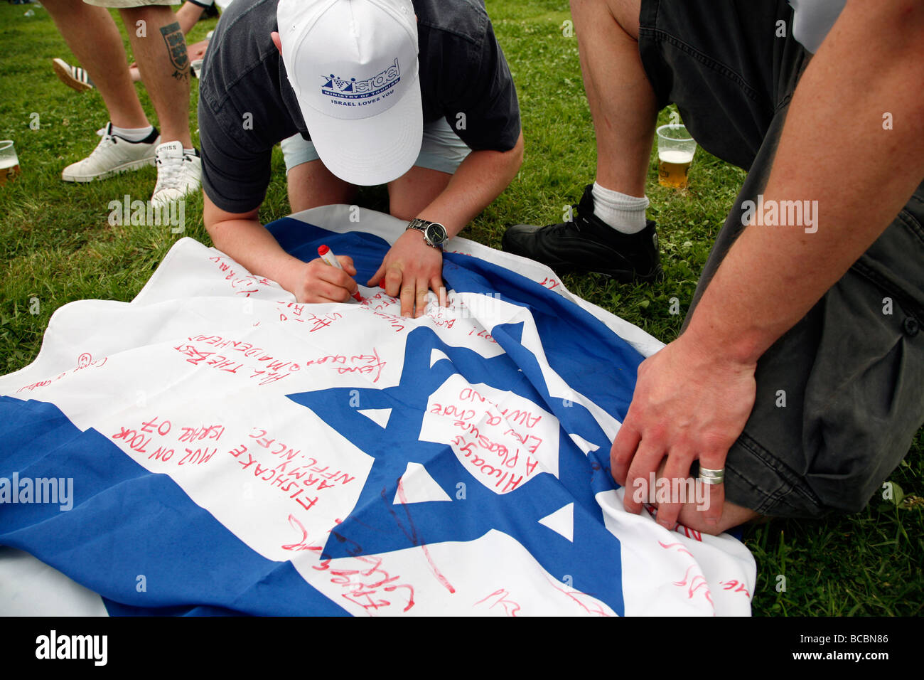 English football fans writing messages on an Israeli flag in Tel Aviv ...