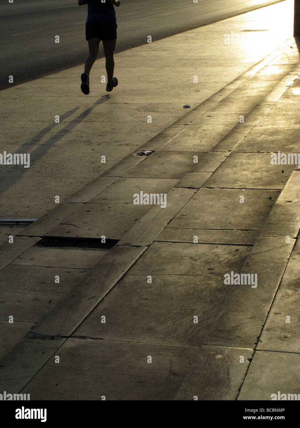one fast runner in action on street in city town in morning sun Stock ...
