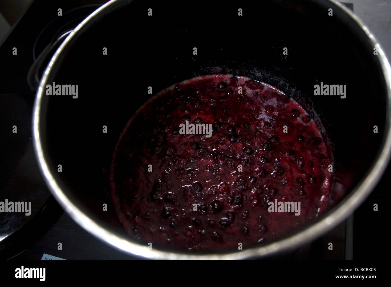 Red currants cooking in large black saucepan Stock Photo - Alamy