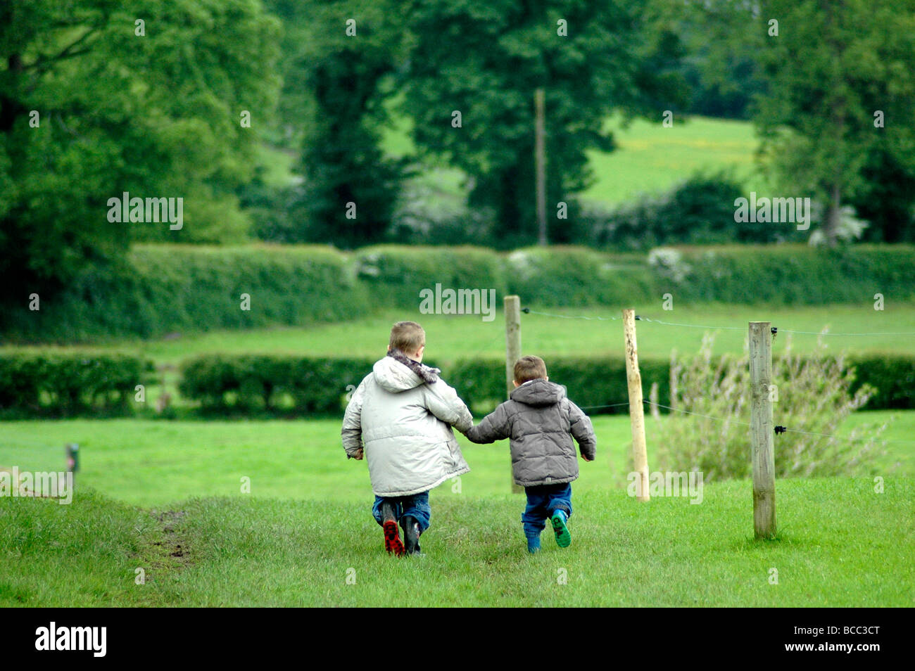 Two children walking holding hands Stock Photo - Alamy