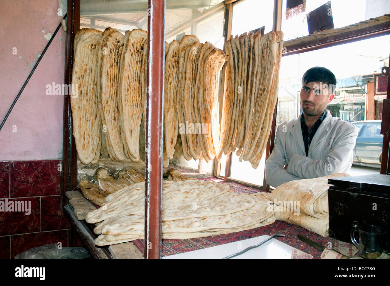 A customer waits to buy bread, nan, at the streetside hatch of a ...