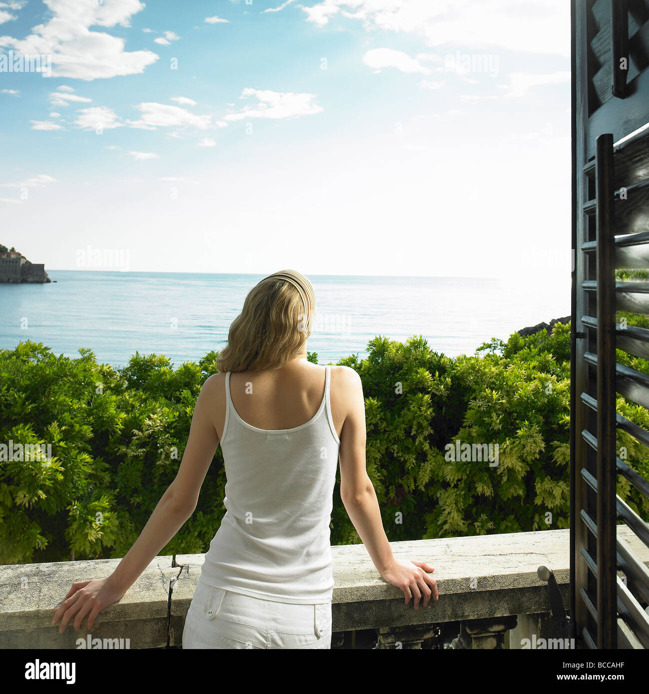 Woman on terrace looking out to sea Stock Photo - Alamy