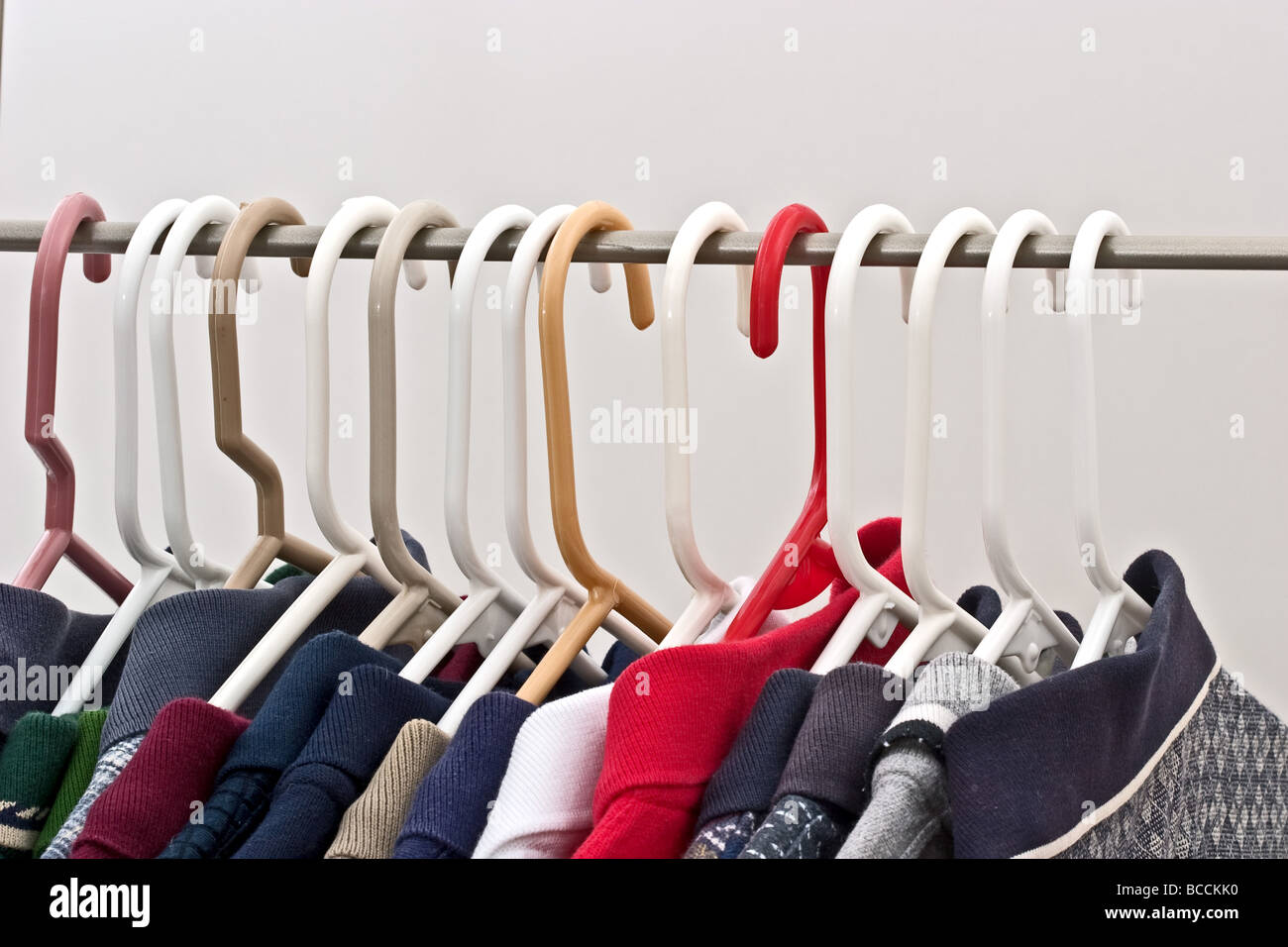 Shirts on hangers on a metal rack, with one red shirt out of place ...