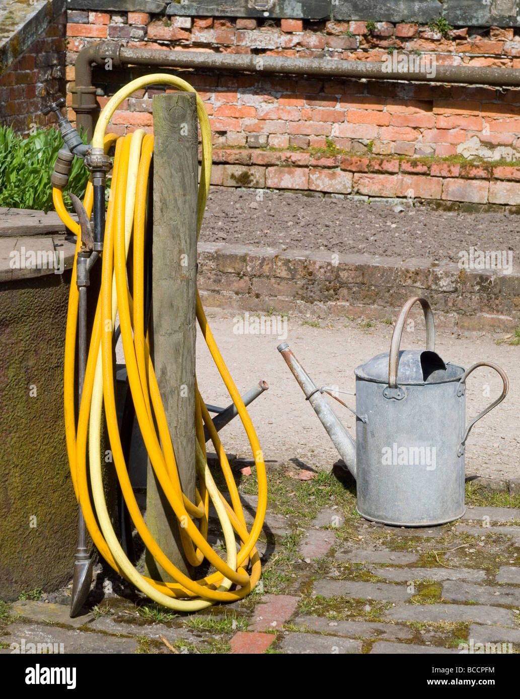 An old metal watering can and garden hose, England UK Stock Photo - Alamy