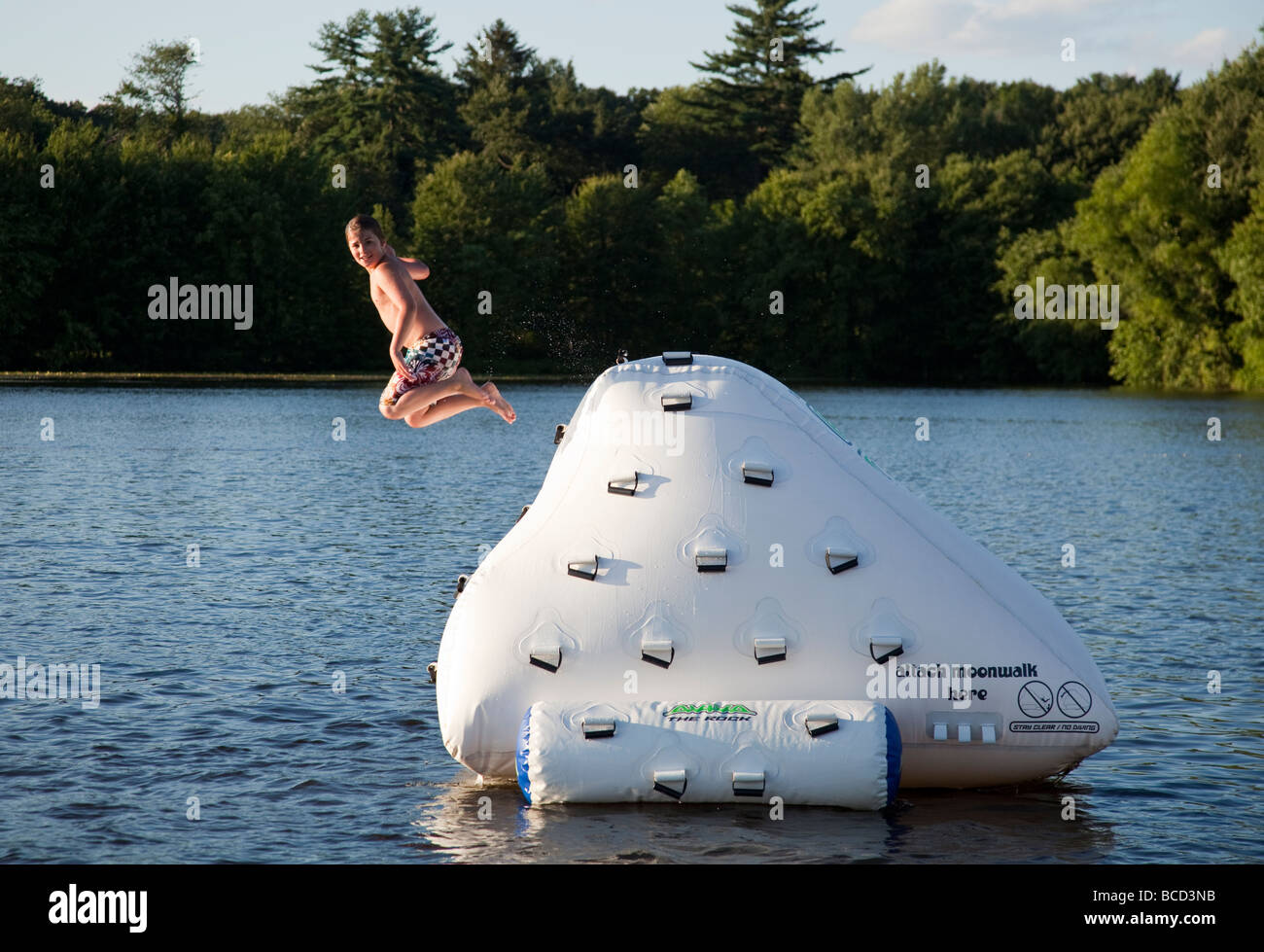 Boy jumping off an inflatable raft into a lake Stock Photo - Alamy