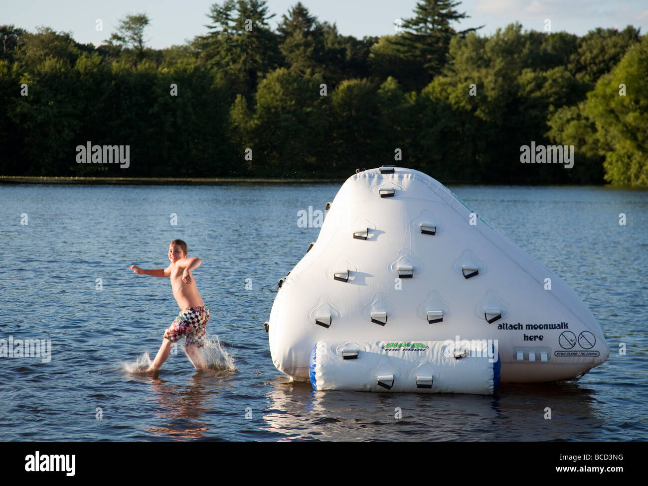 Boy jumping off an inflatable raft into a lake Stock Photo - Alamy