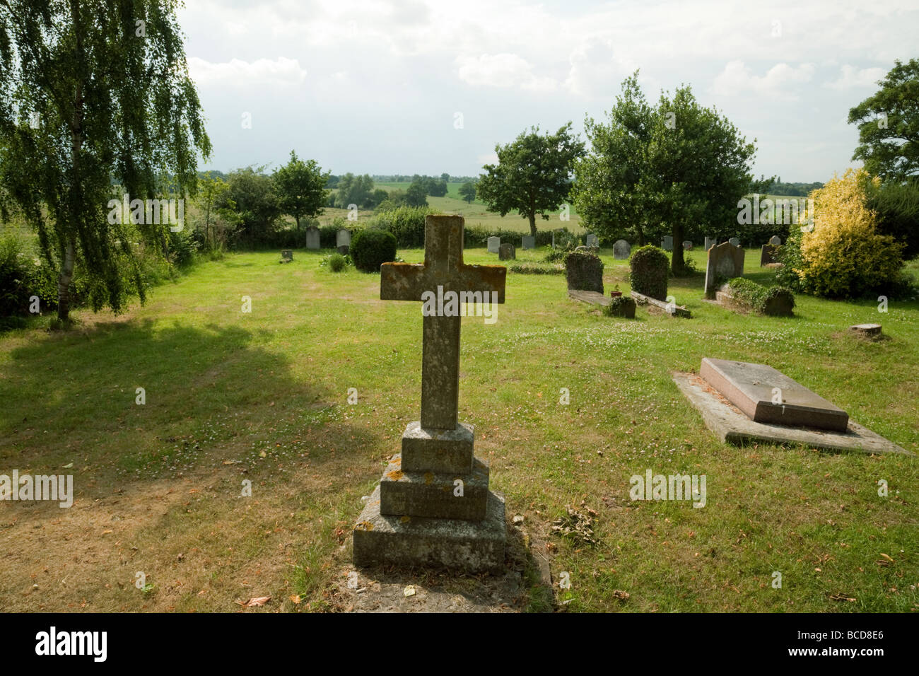 A cross in an English country graveyard looking out over fields, Essex ...