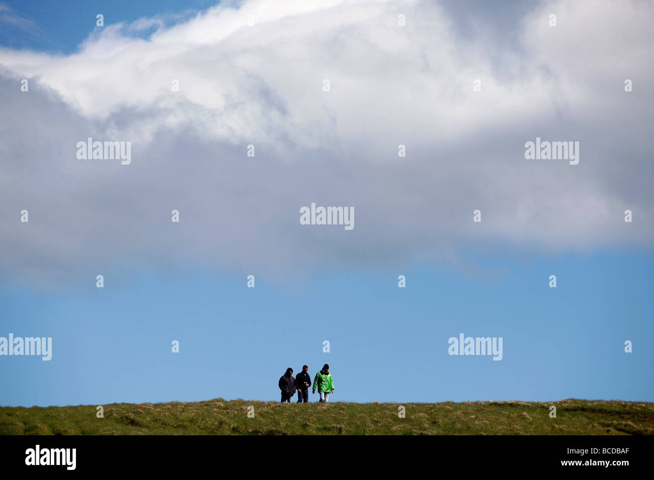 Three people walk along a ridge on Grímsey Island on the Arctic Circle ...