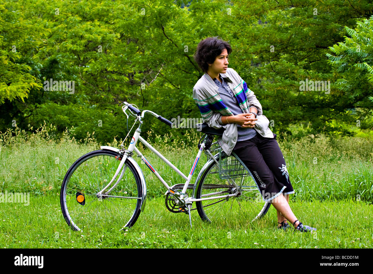 Girl leaning on bicycle in green grass Stock Photo - Alamy