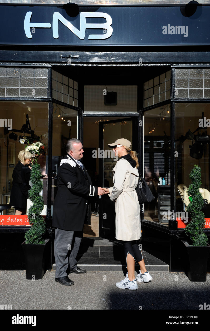 A HAIRDRESSING SALON WITH A CONCIERGE GREETING A CLIENT IN THE DOORWAY ...