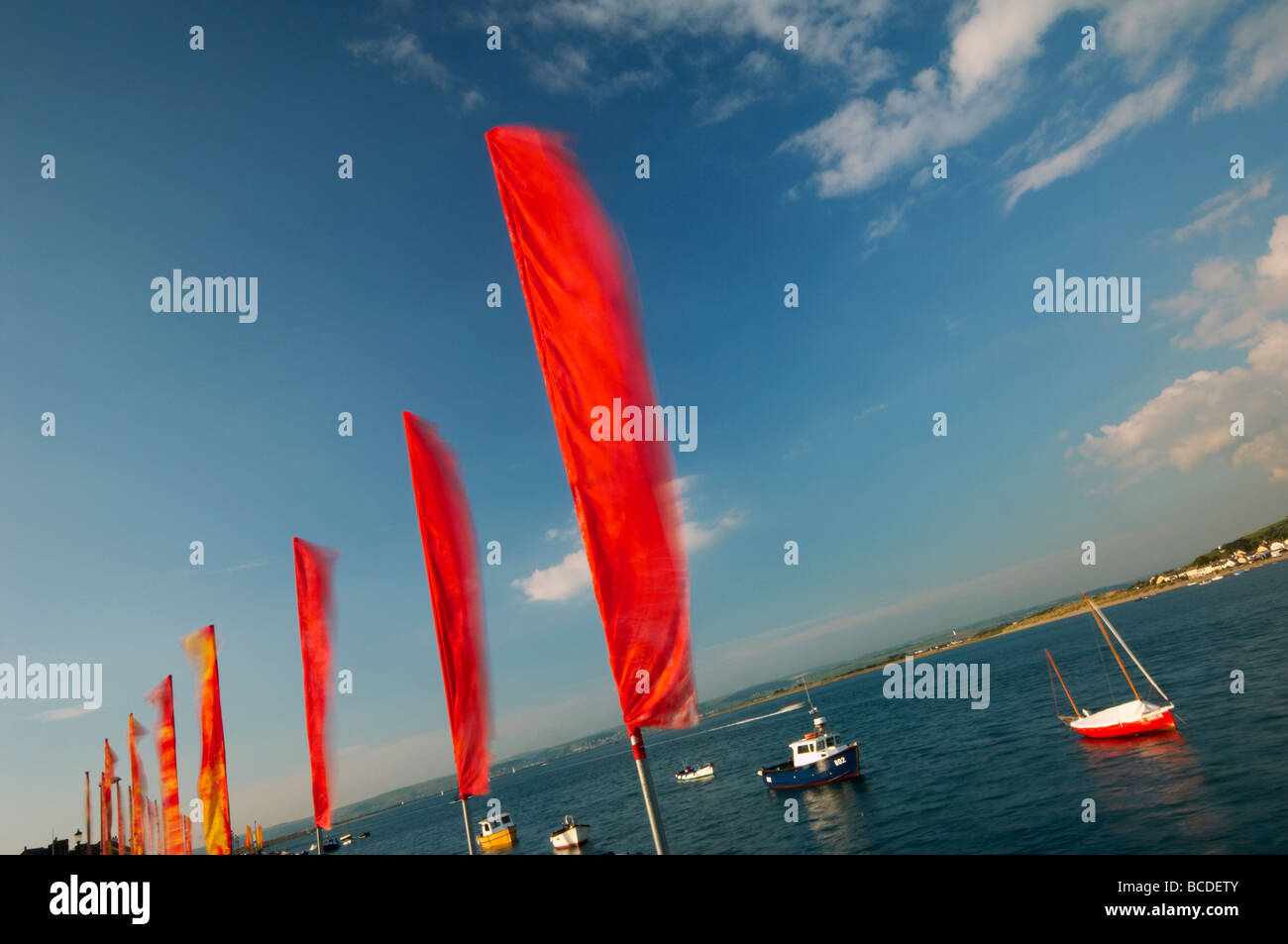 Crowds of people walking past brightly coloured flags flapping in the ...