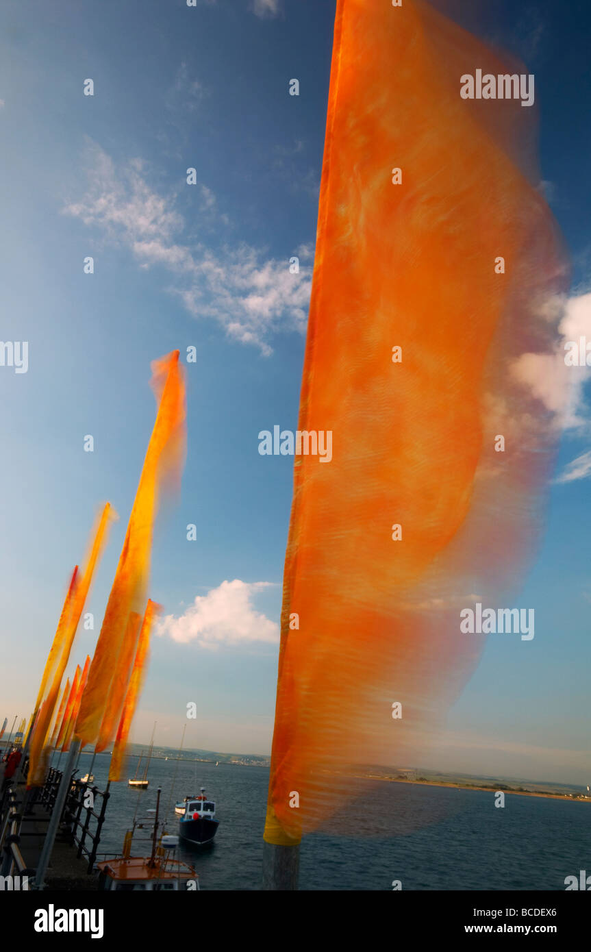 Crowds of people walking past brightly coloured flags flapping in the ...