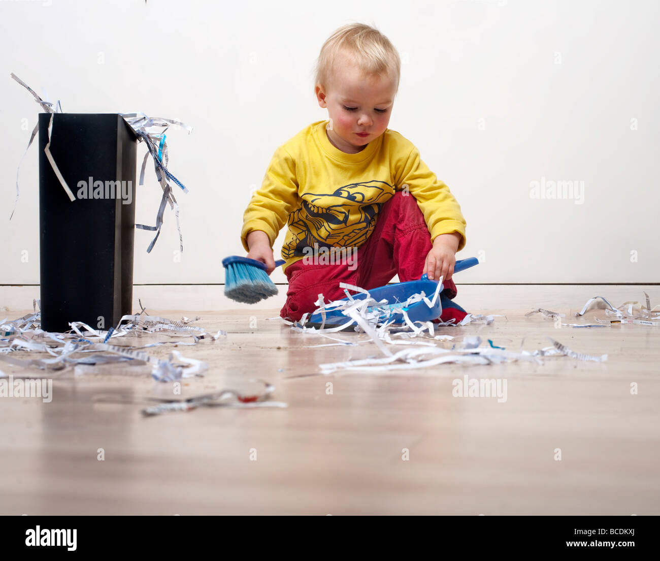 Young child cleaning up shredded paper Stock Photo - Alamy