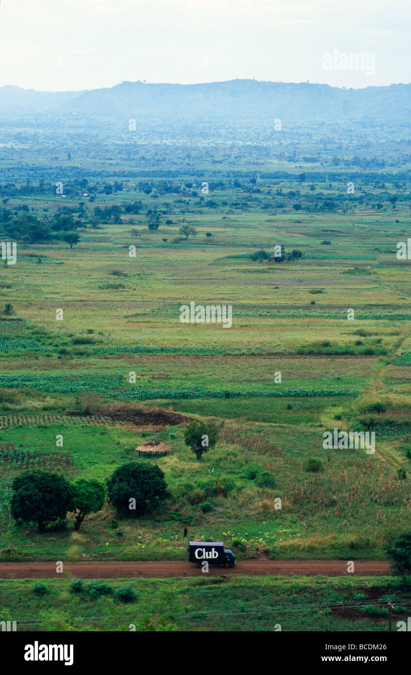 Aerial view of a dirt road, African farmland, crops and a rustic hut ...