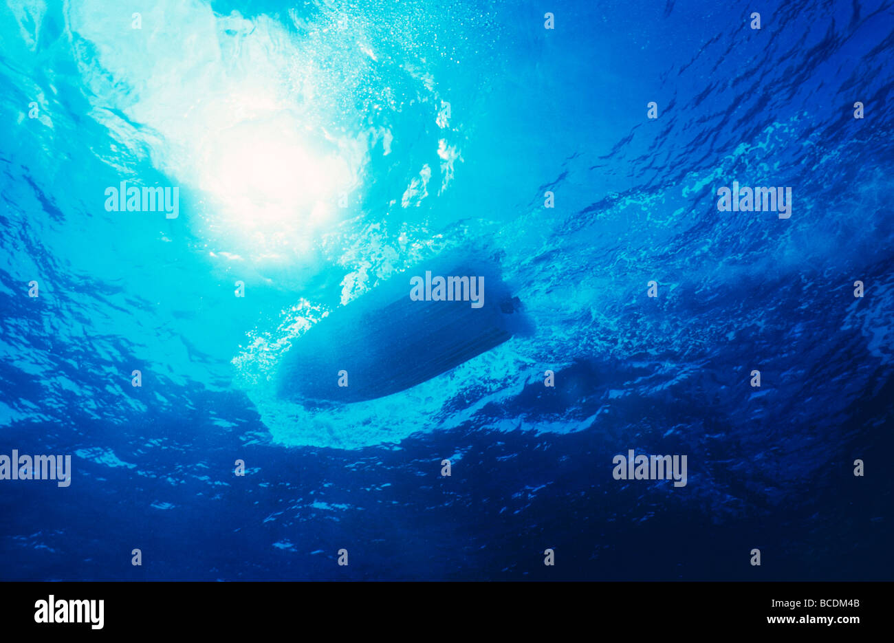 The hull of a speed boat dingy races on the ocean surface from below ...