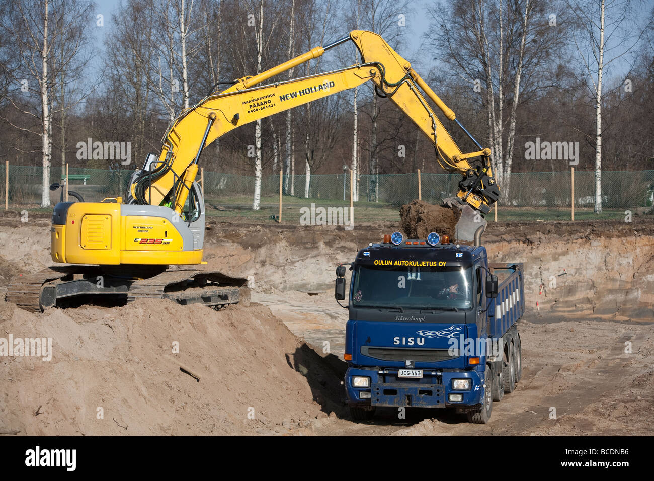 Digger loading dirt to dump truck at construction site pit , Finland ...