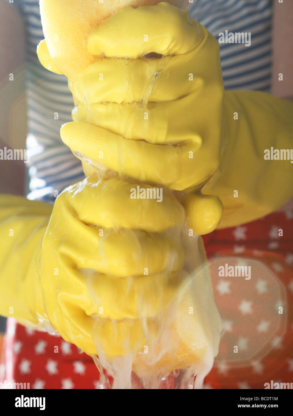 A close up of women wringing out a sponge, wearing yellow plastic ...