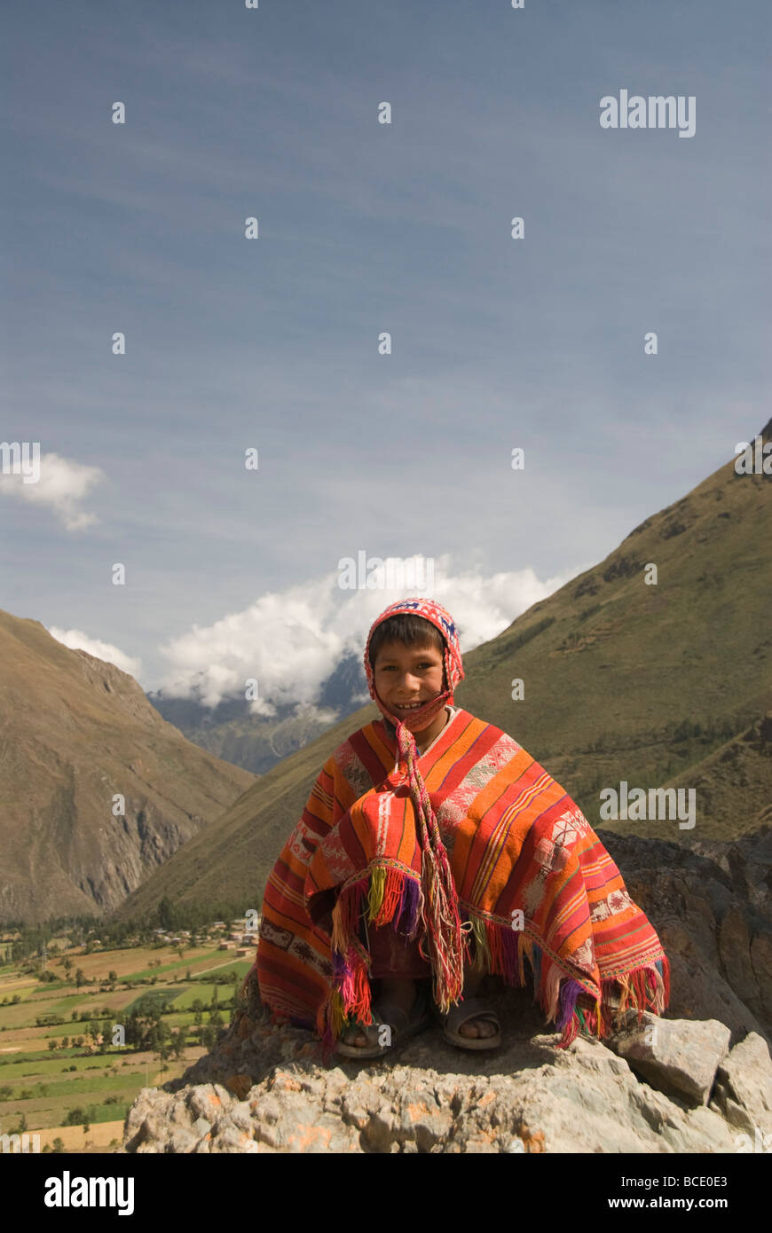 Incan boy sitting on rock above the Sacred Valley, near the village of ...