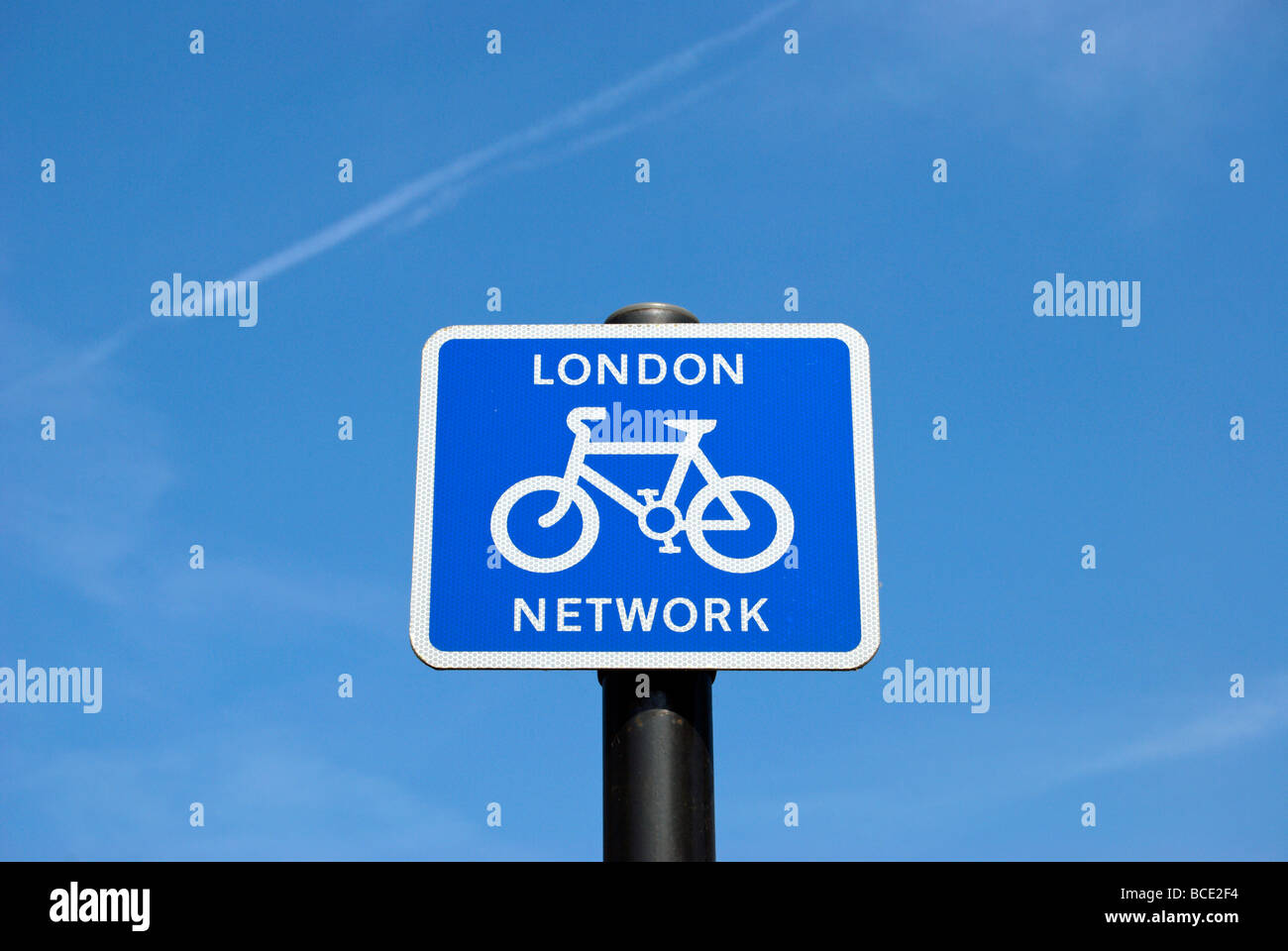 london network cycling sign seen against a blue sky with vapour trail ...