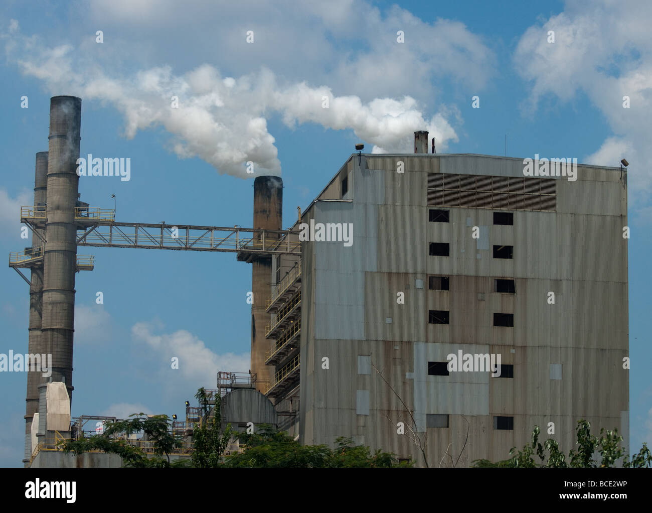 Industry. A paper mill building with steam or smoke plumes against a ...